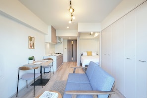 Um apartamento moderno com cozinha compacta, sala de jantar, sofá e guarda-roupa.