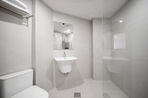 Uma casa de banho moderna com sanita, lavatório e chuveiro.