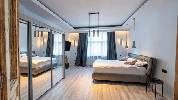 Quarto moderno com cama grande, área de dormir separada e porta de vidro deslizante para uma varanda.