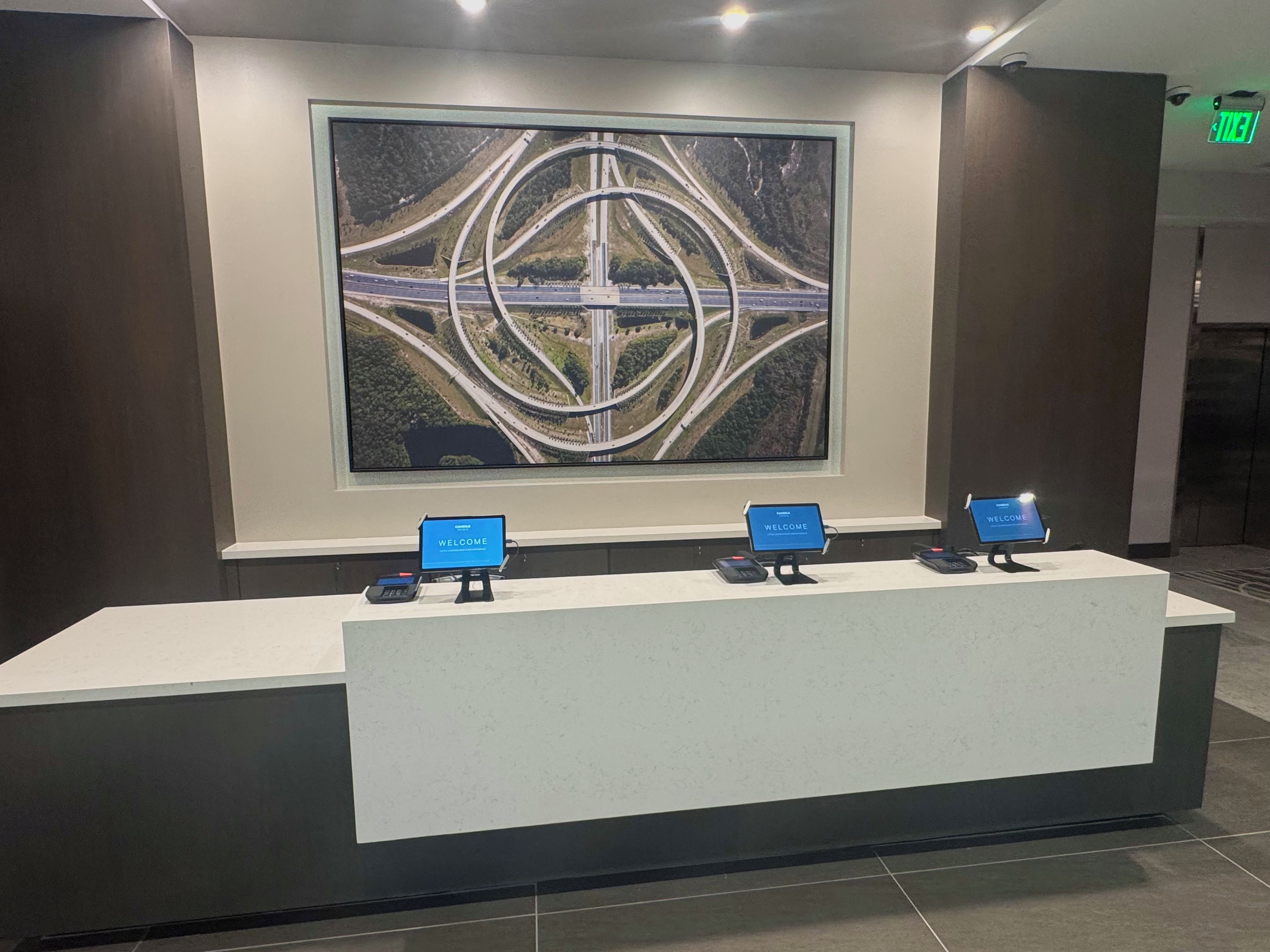 Uma receção com um grande mapa rodoviário emoldurado acima e dois ecrãs digitais de boas-vindas.