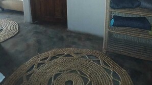 Um quarto com porta de madeira, um quadro de um veleiro e esteiras trançadas no chão.