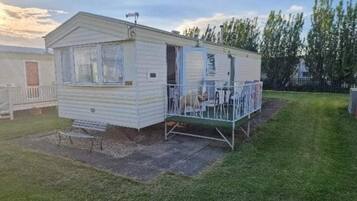Uma casa móvel com varanda cercada e um pequeno alpendre.