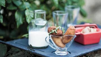 Uma tigela de vidro com dois alimentos fritos, uma garrafa de leite e um recipiente vermelho com um objeto branco sobre uma superfície azul.