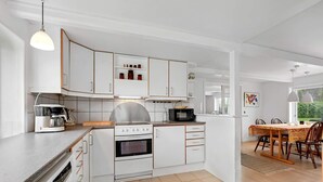 Uma cozinha moderna com armários brancos, forno embutido, micro-ondas e cafeteira.