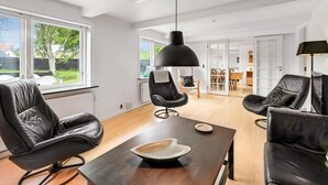 Uma sala de estar moderna com poltronas de couro, uma mesa de centro de madeira escura e uma luminária pendente.