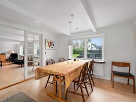 Espaço de refeições com mesa, cadeiras e vista para o exterior.