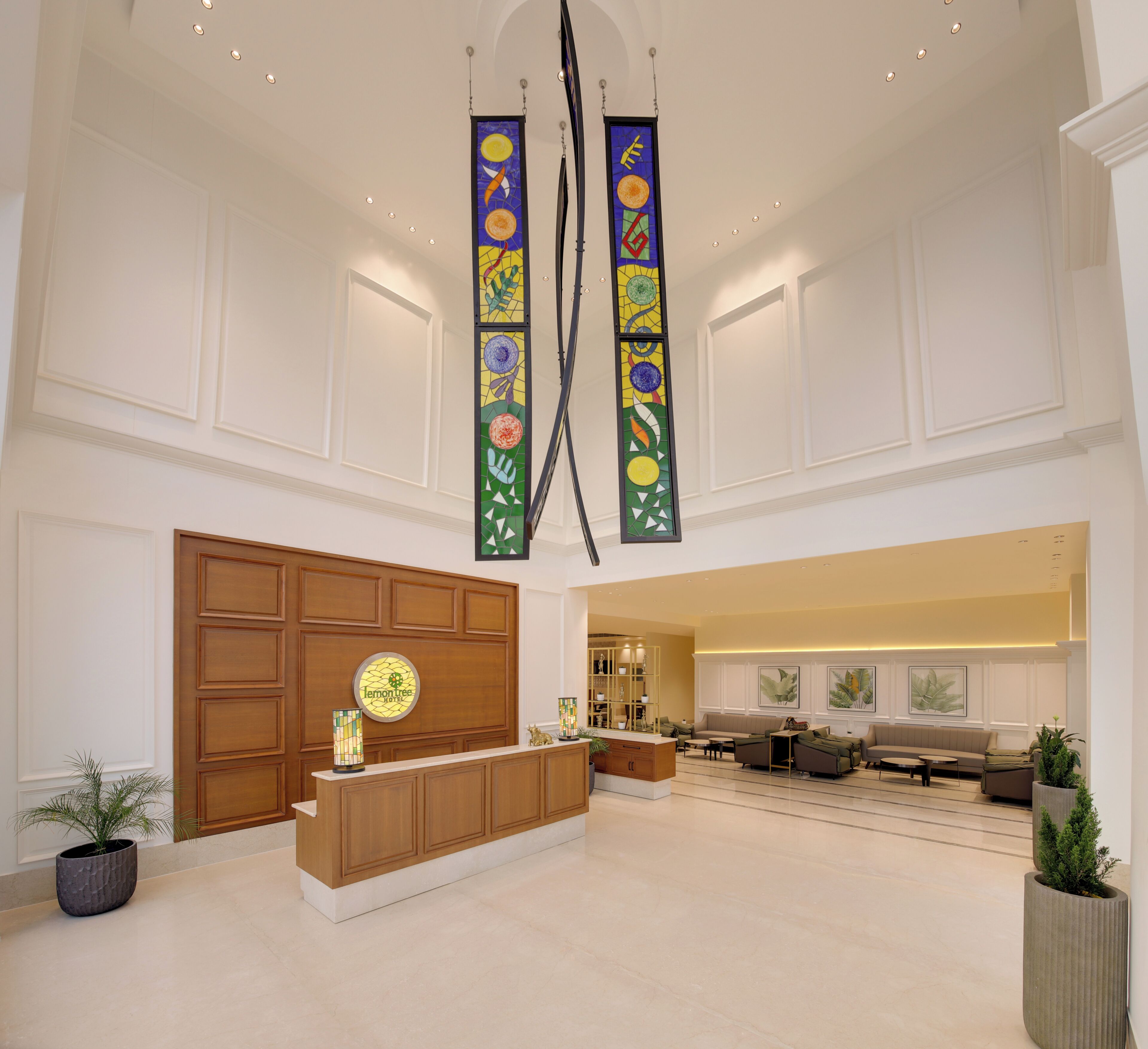 Um amplo hall de entrada com balcão de recepção, área de estar e duas janelas com vitrais.