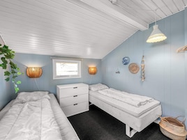 Quarto com duas camas, janela, luminárias fixadas na parede e ventilador de teto.