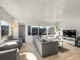 Uma sala de estar moderna com sofá, mesa de centro, TV e estante.