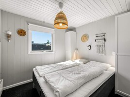 Quarto com cama, janela, relógio de parede e luminária pendente.
