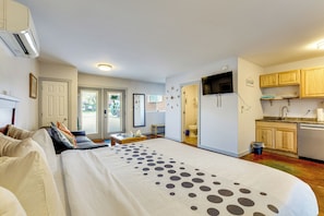 Quarto com cama, sofá, escrivaninha e vista para o exterior.