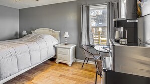 Quarto com cama, mesa de cabeceira, luminária, cadeira e vista para uma varanda.