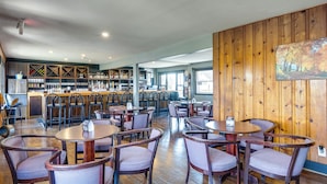Um restaurante com paredes de madeira, um bar e vários arranjos de mesas.