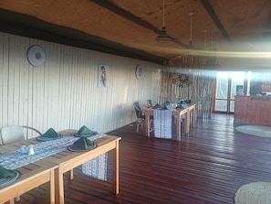 Um quarto com piso de madeira, uma mesa de jantar com jogos americanos verdes e uma parede com ripas de madeira verticais.