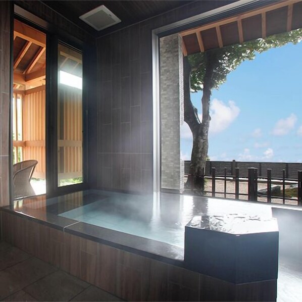 Uma área de spa moderna com um banco de madeira, uma parede de pedra e vista para o céu.