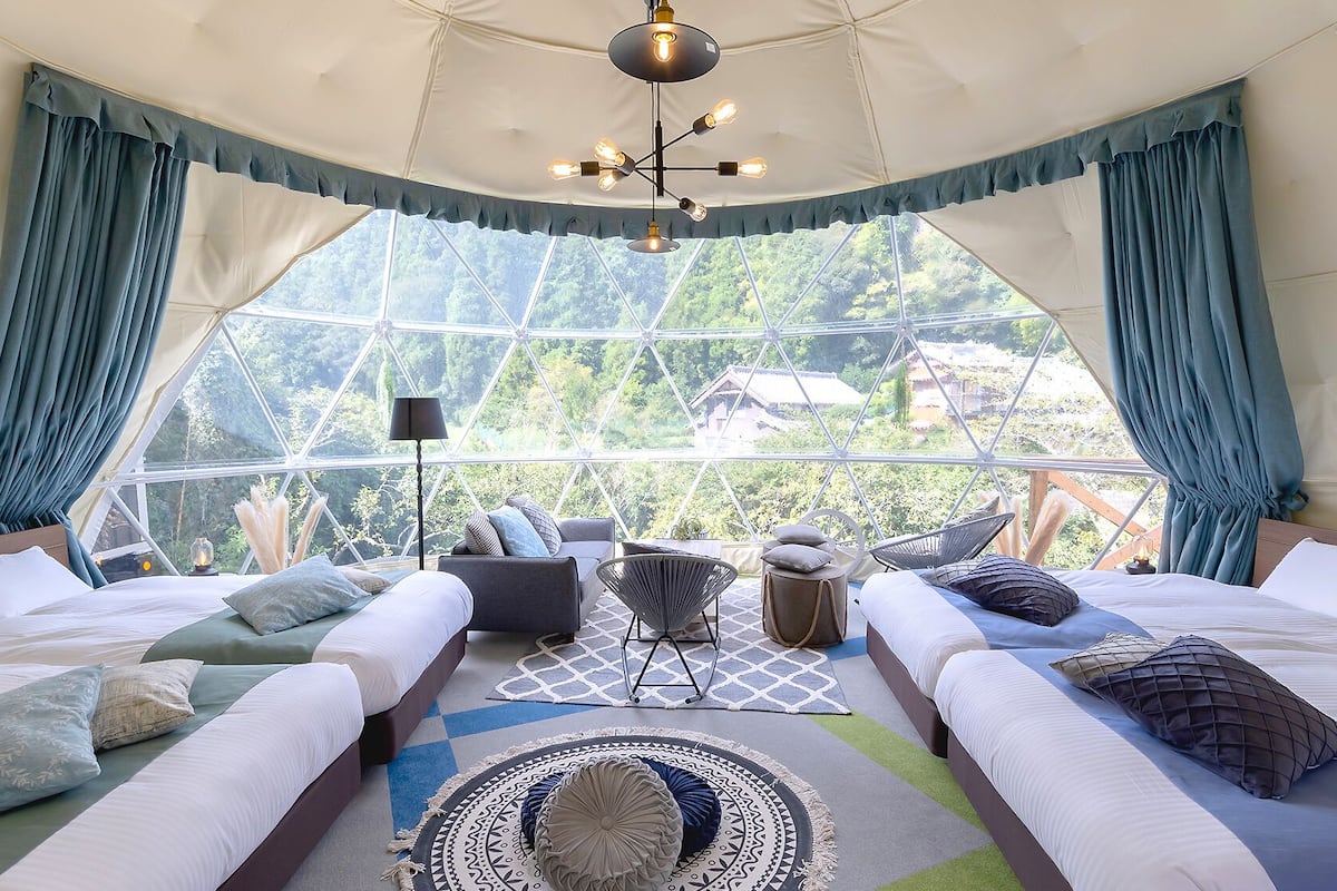 Acomodação em tenda com duas camas, uma área de estar central e vista para o exterior.