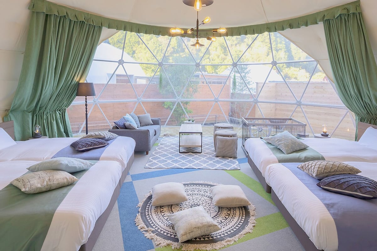 Quarto com duas camas, um sofá, uma mesa de centro e vista através de amplas janelas.