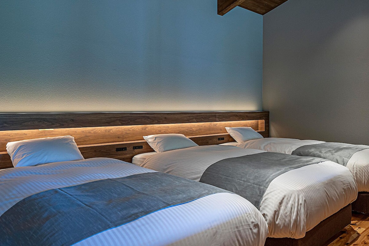 Quarto de hotel com uma cama grande, cabeceira de madeira e design simples e clean.