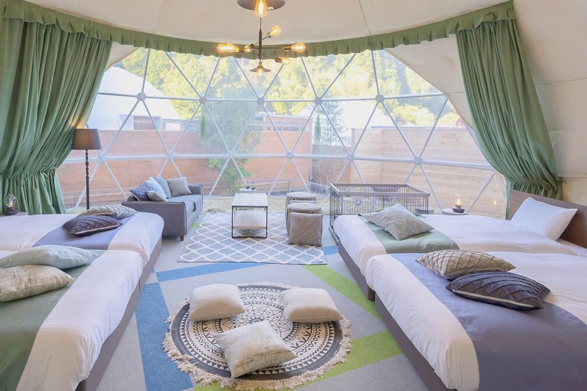 Um quarto acolhedor com duas camas, um sofá, uma mesa pequena e vista através de grandes janelas.