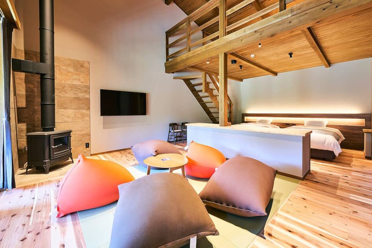 Um interior moderno com piso de madeira, um sofá, uma cama, uma televisão e uma lareira.