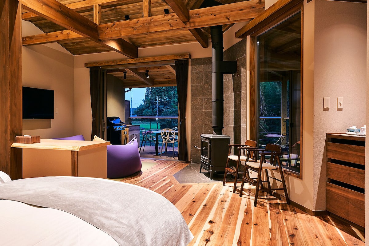 Quarto moderno com teto de madeira, uma cama, uma escrivaninha e vista para o exterior.