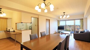 Sala moderna com mesa de jantar, sofá e televisão. Possui uma varanda com vista.