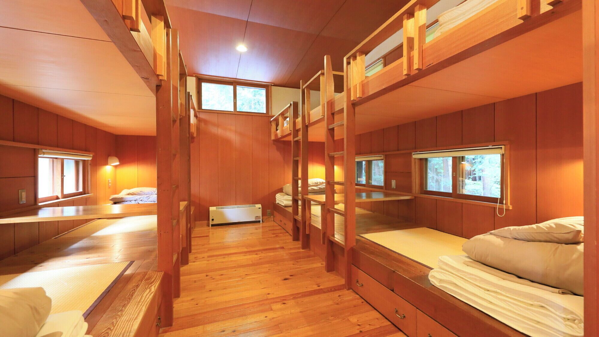Uma cabana com beliches, piso de madeira e janelas.