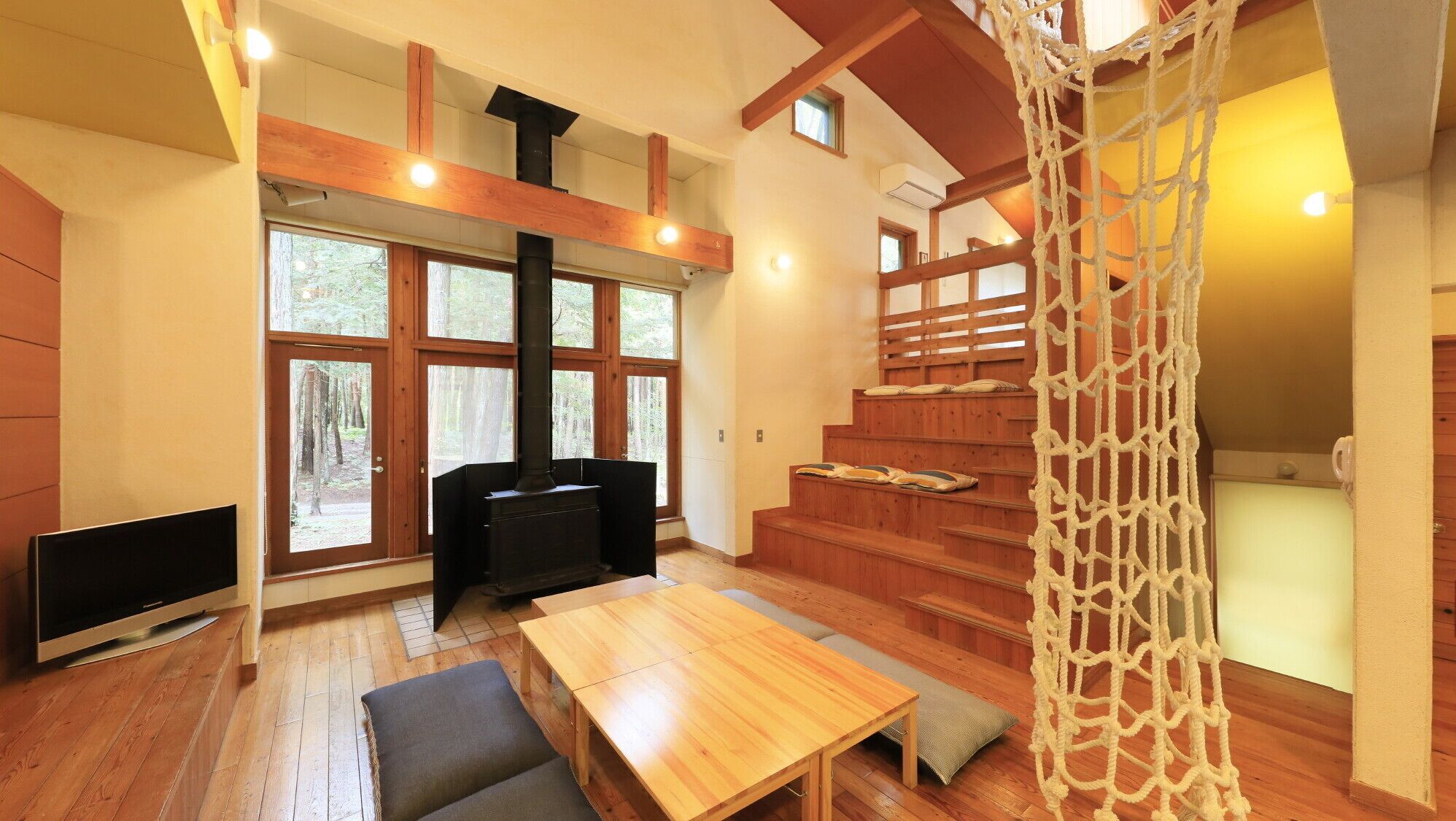 Interior de madeira com lareira, televisão e escada.