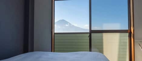 Quarto com cama e janela com vista para uma montanha.