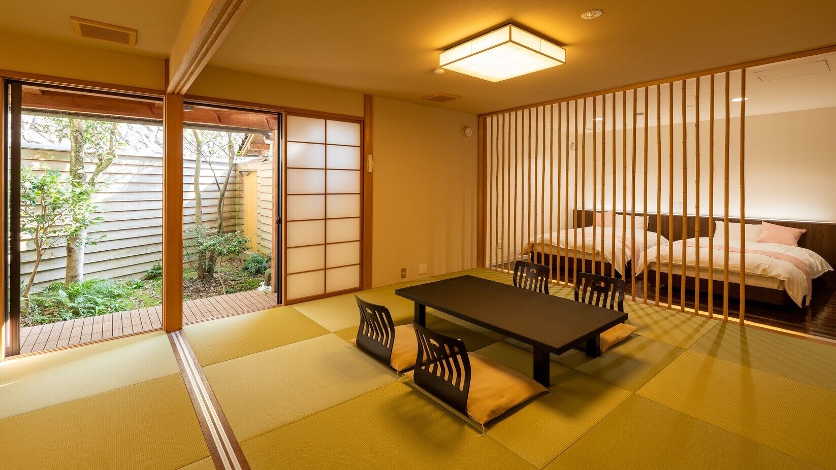 Um quarto japonês tradicional com tatame, uma mesa baixa e uma cama com divisória shoji.