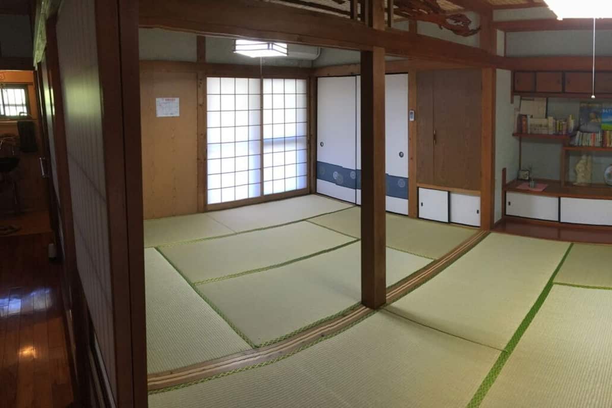 Um quarto japonês tradicional com piso de tatame, portas deslizantes e uma estante de livros.