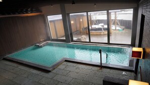 Piscina interna com vista para uma área externa coberta de neve através de grandes janelas.