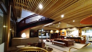 Um interior moderno com escada de madeira, áreas de estar e um balcão.