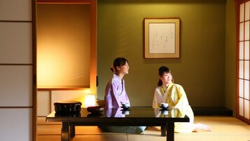 Um quarto japonês tradicional com tatames, uma mesa baixa e um painel de caligrafia na parede.