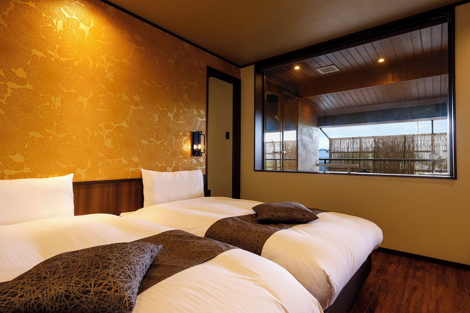 Quarto de hotel com uma cama grande, janela com vista e parede estampada.