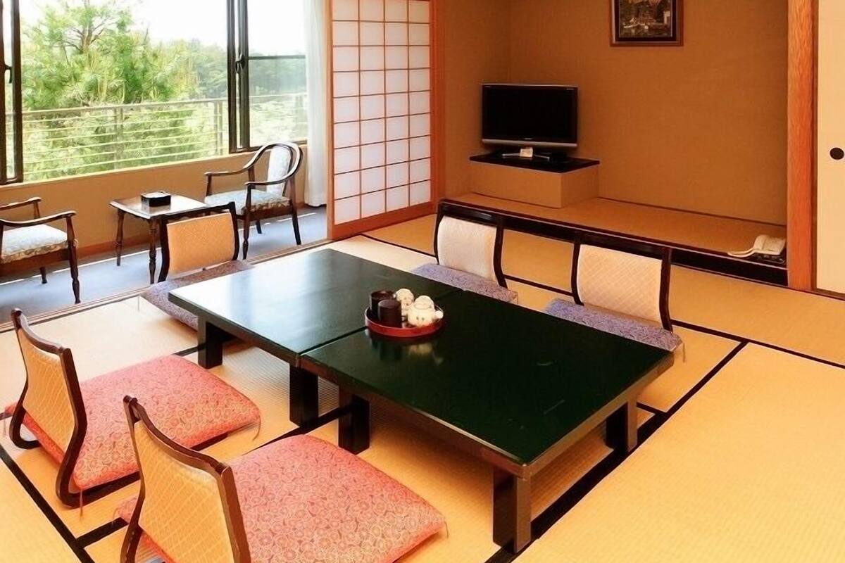 Um quarto em estilo japonês tradicional, com tatames, uma mesa baixa e biombos shoji.