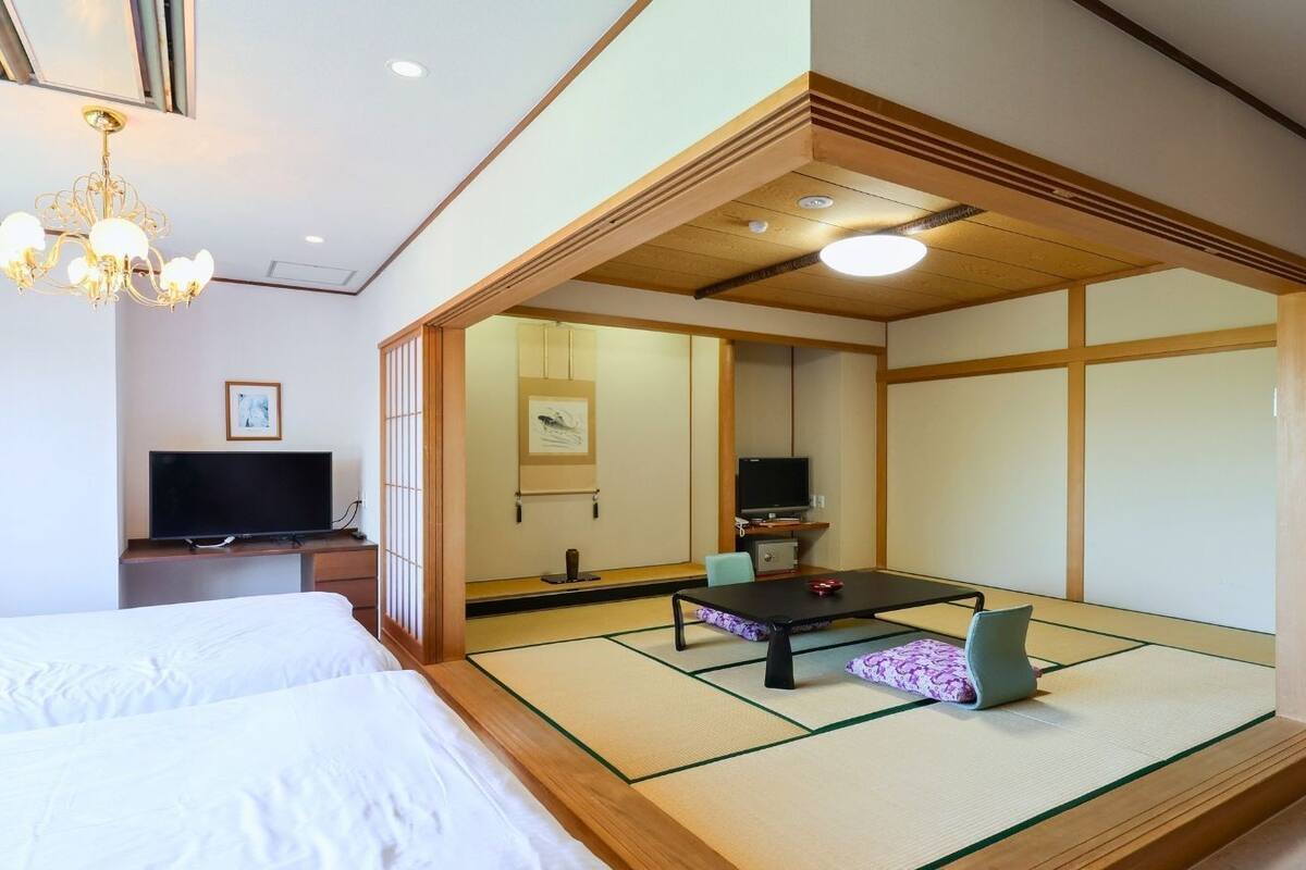 Um quarto japonês tradicional, com tatames, uma mesa baixa e uma televisão.
