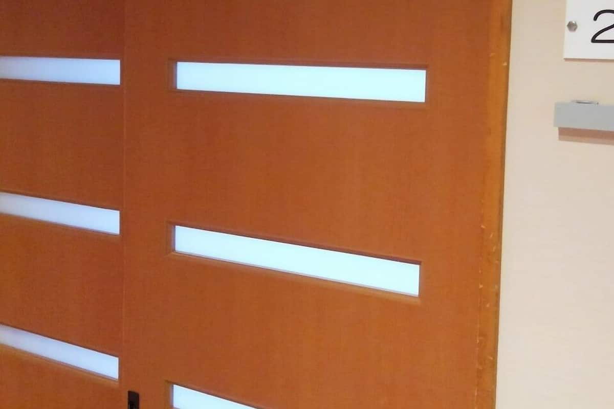 Uma porta de madeira com ripas horizontais e uma etiqueta branca com o número '2' na parede à direita.