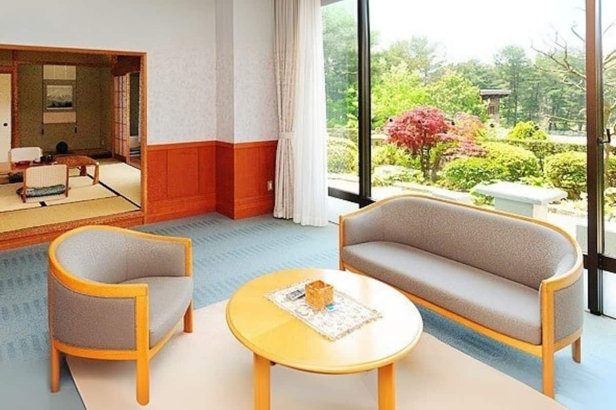 Quarto de hotel com sofá, poltrona e mesa redonda.
