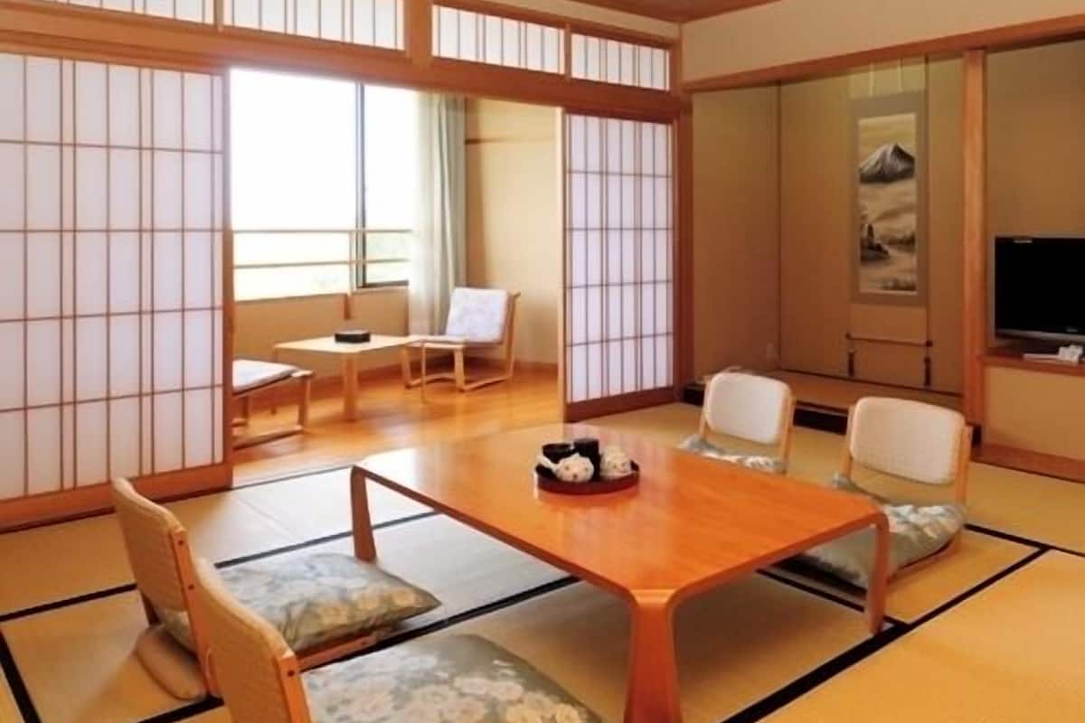 Um quarto em estilo japonês tradicional, com tatames, uma mesa de madeira baixa e biombos shoji.