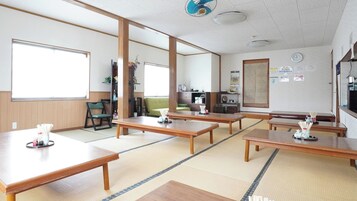 Um quarto japonês tradicional com tatames, mesas de madeira e um sofá verde.