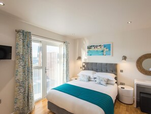 Quarto com cama, cortinas, um quadro, luminária de cabeceira, espelho e mesa de cabeceira.