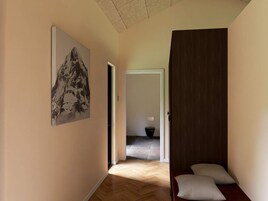Um corredor com piso de madeira, porta de madeira escura e um quadro na parede.