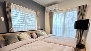 Quarto de hotel com duas camas, televisão de tela plana e ar condicionado.