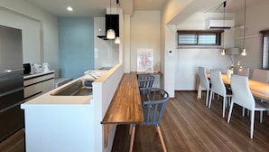 Cozinha moderna com ilha central, área de refeições com cadeiras e forno embutido.