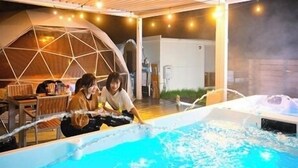 Uma banheira de hidromassagem com um deck de madeira e uma estrutura tipo tenda ao fundo.