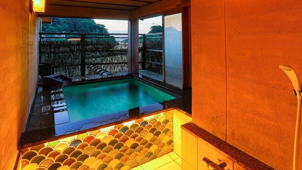 Piscina com vista para árvores e um cercado, piso ladrilhado e área de chuveiro.