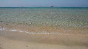 Uma praia com águas cristalinas, areal arenoso e ilhas ao longe.