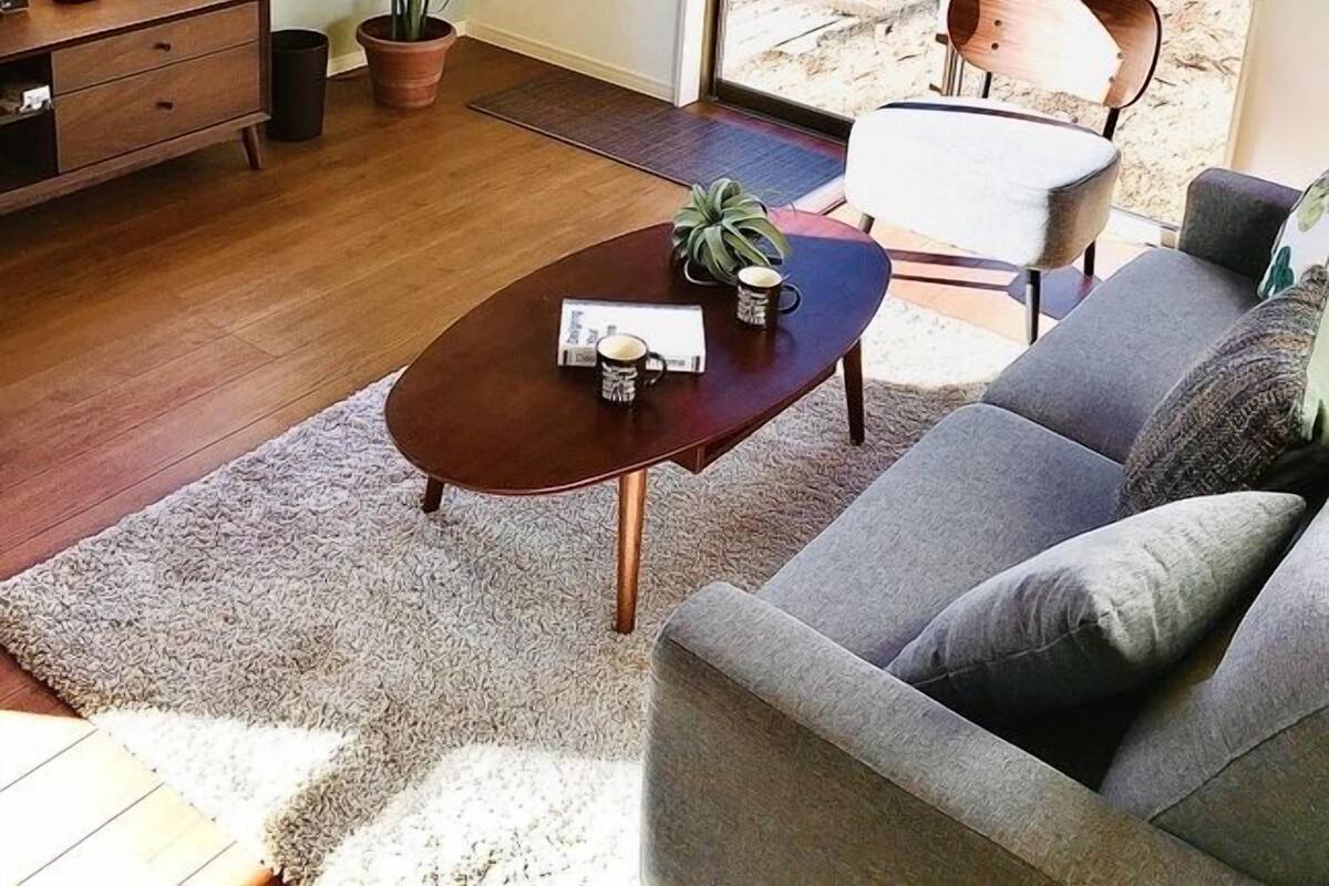 Sala de estar com sofá, mesa de centro e vista para área externa nevada através de grandes portas de vidro.