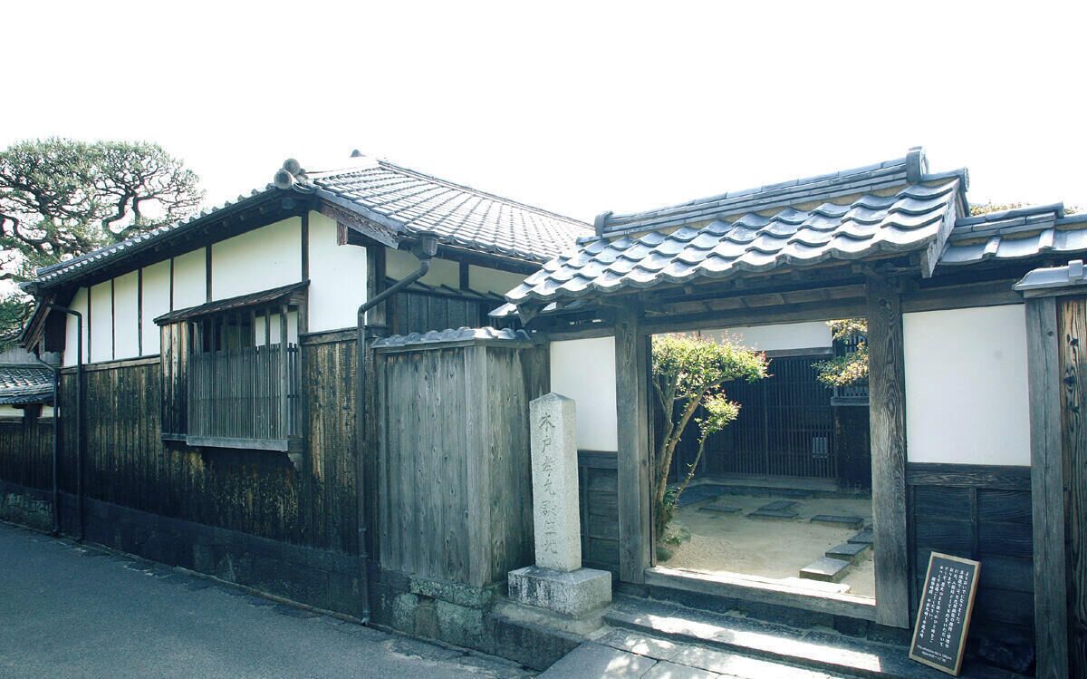 Um edifício japonês tradicional com telhado de telhas, paredes de madeira e um pilar de pedra.